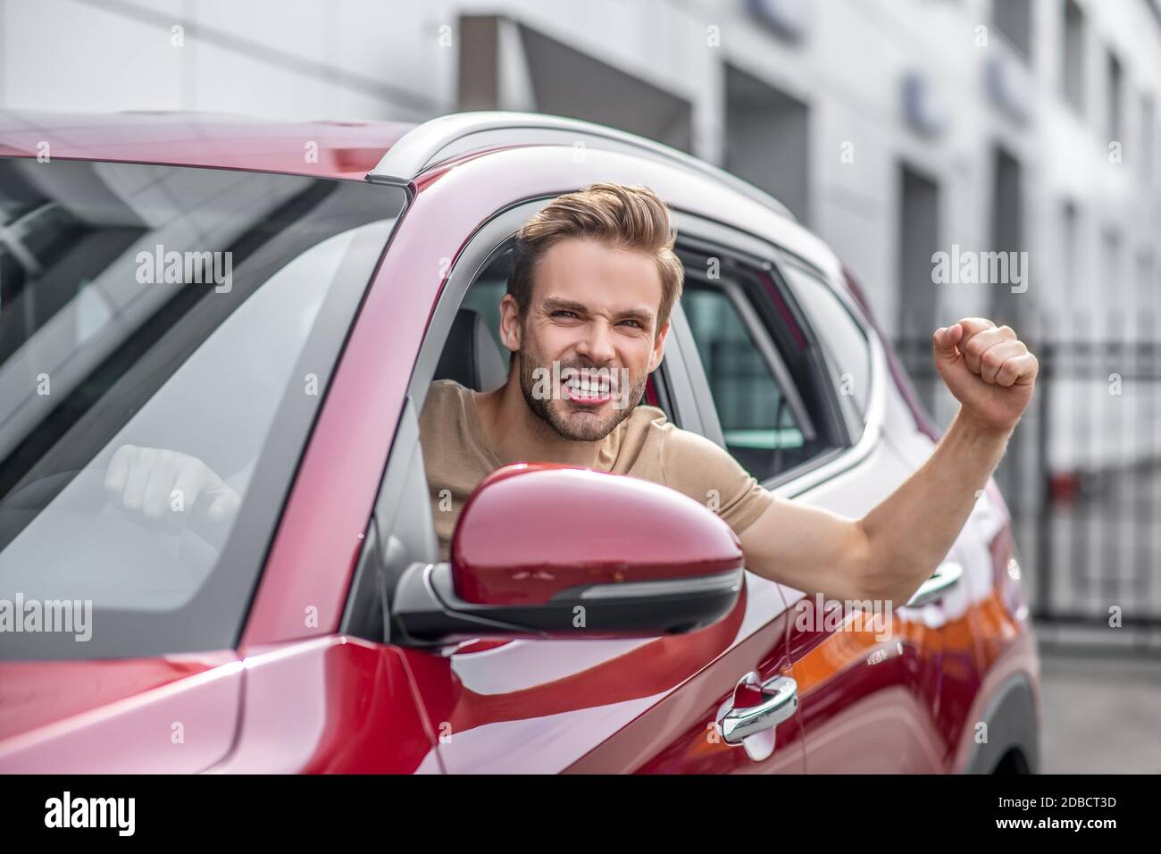 Excited male driving car, raising hand in the air Stock Photo - Alamy