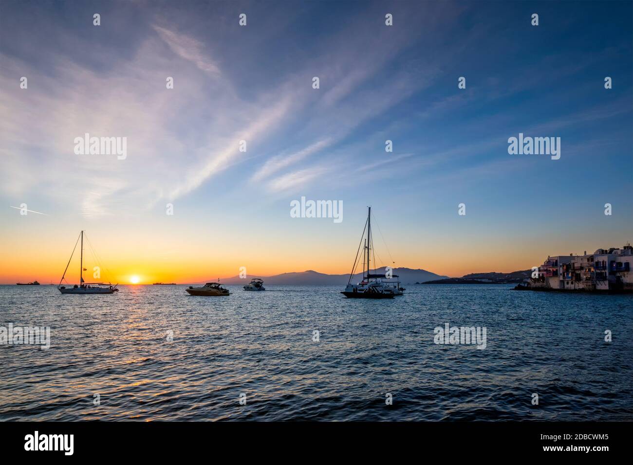 Sunset in Mykonos island, Greece with yachts in the harbor and colorful ...