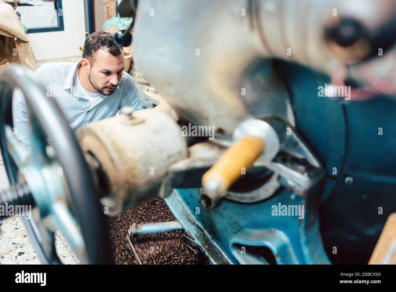 Man operating coffee roaster in his factory Stock Photo - Alamy