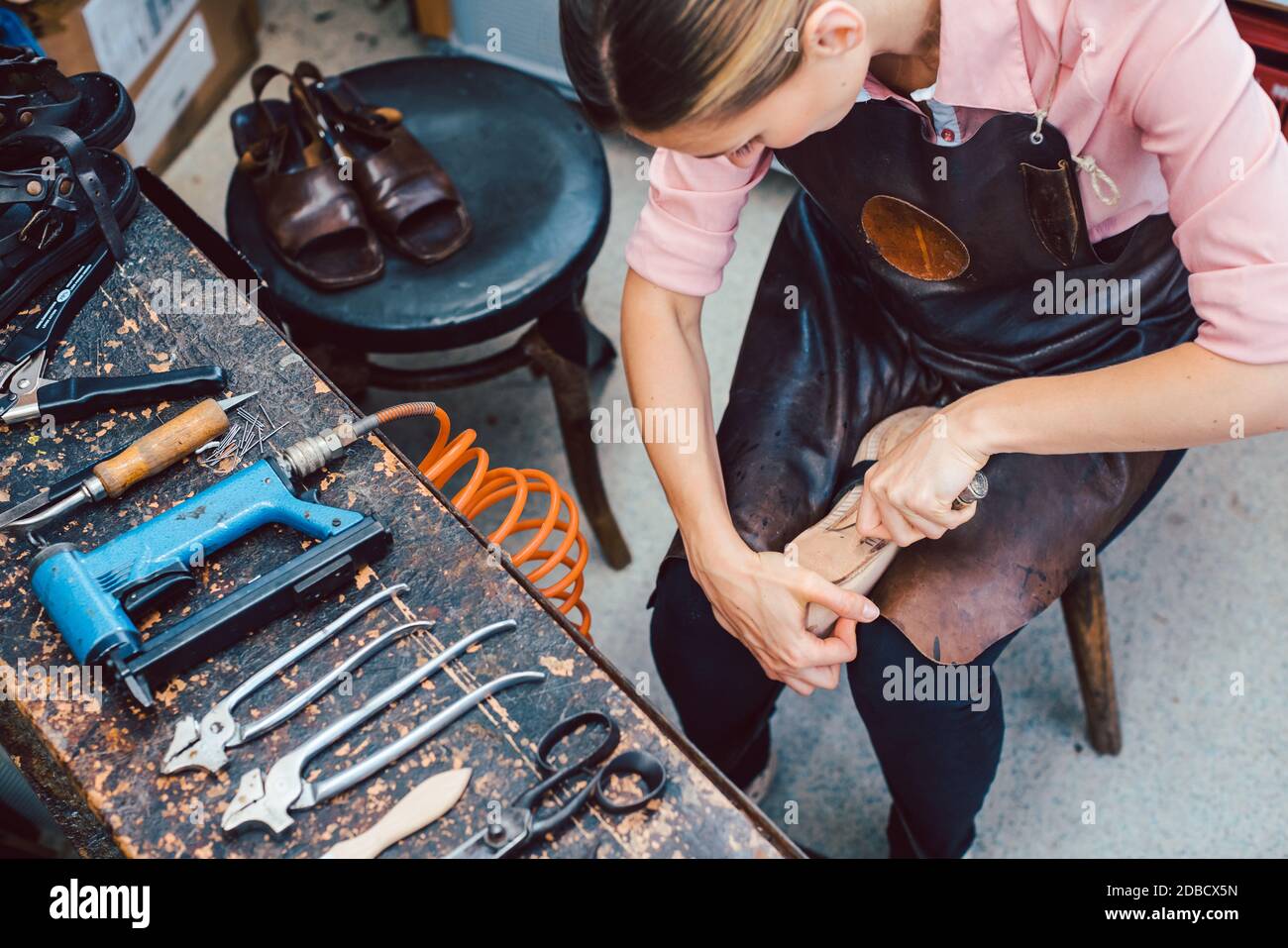 Shoemaker working on the frame of a shoe with lots of tools on the ...