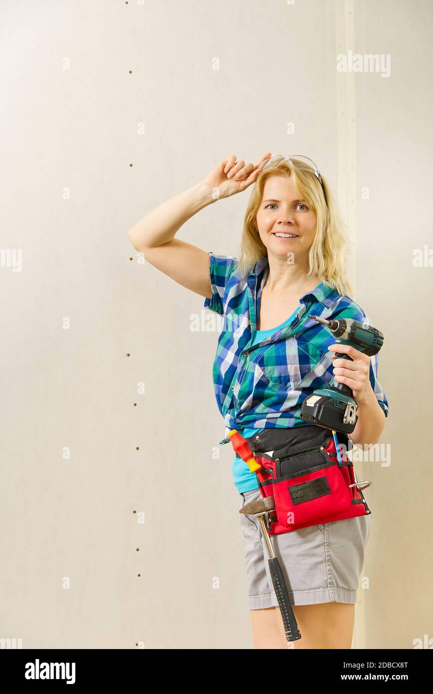 Blond woman wearing a DIY tool belt full of a variety of tools on a ...