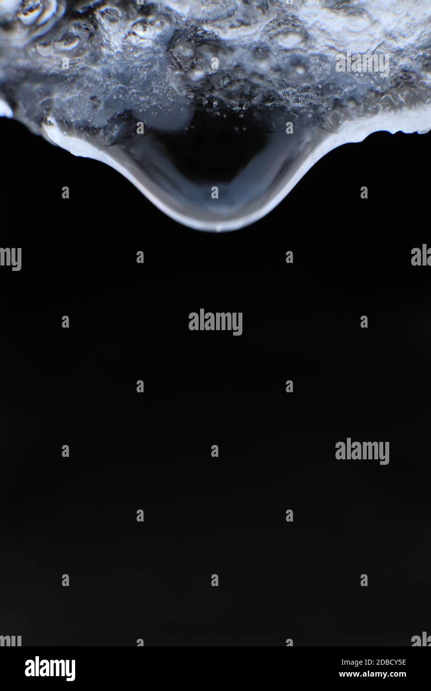 Cold clear rain drop with ice reflection inside. Handing down water ...