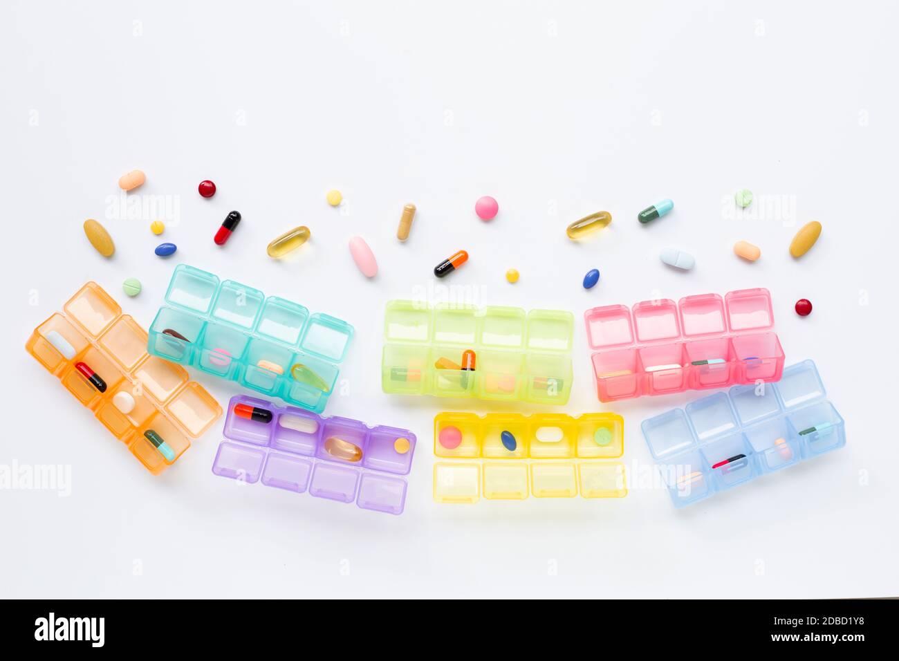 Many colored tablets and capsules with pill box isolated on white ...
