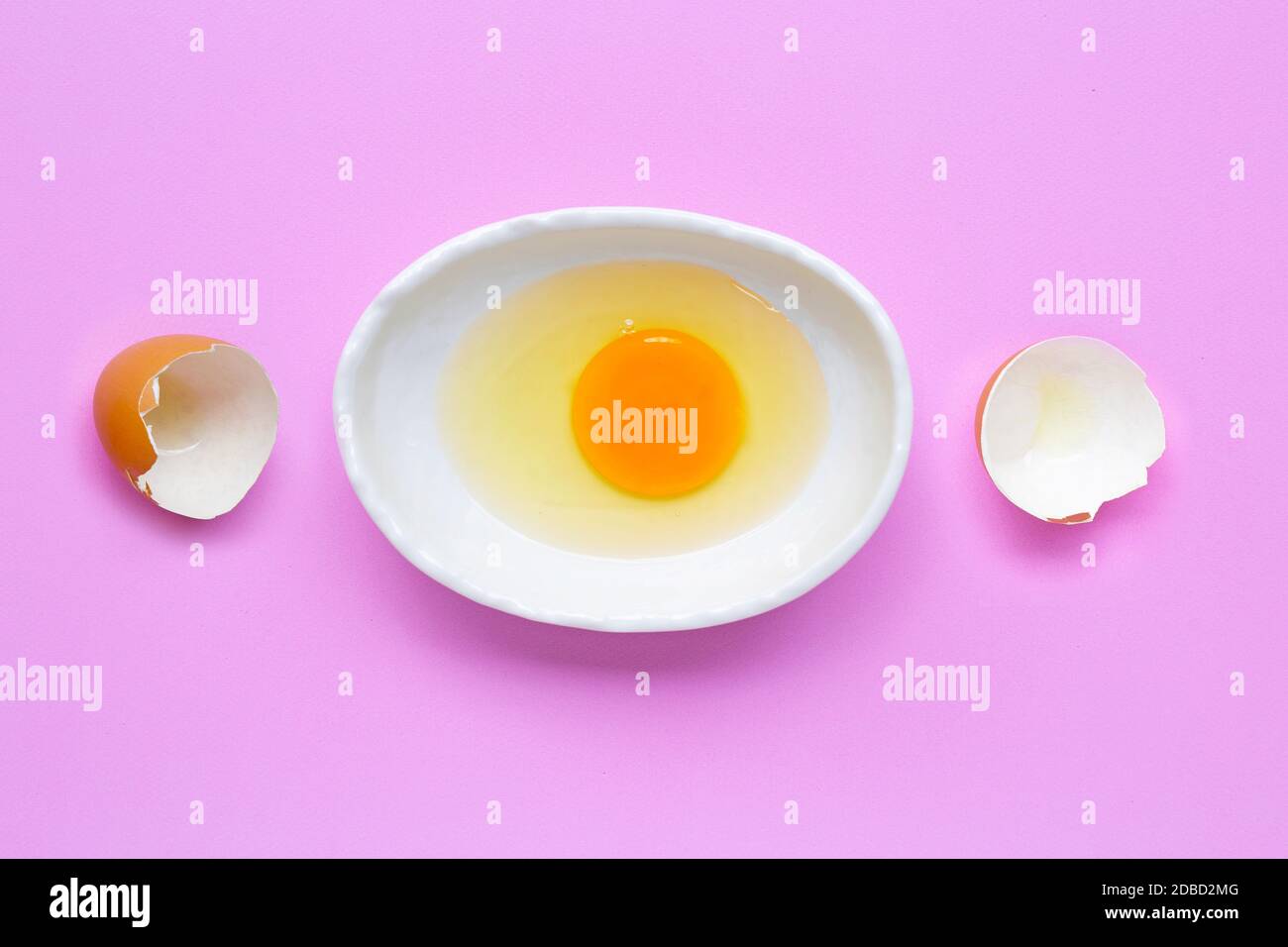 Egg yolk and white in a bowl on pink background. Top view Stock Photo ...