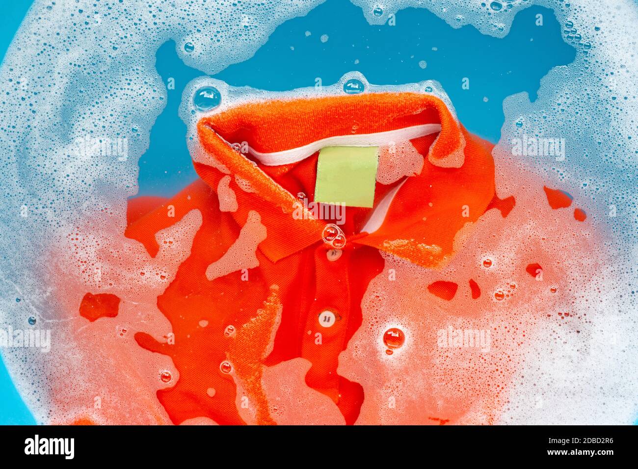 Orange polo shirt soak in powder detergent water dissolution, washing ...