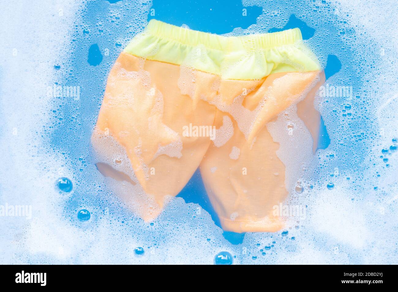 Yellow and orange baby shorts soak in baby laundry detergent water ...