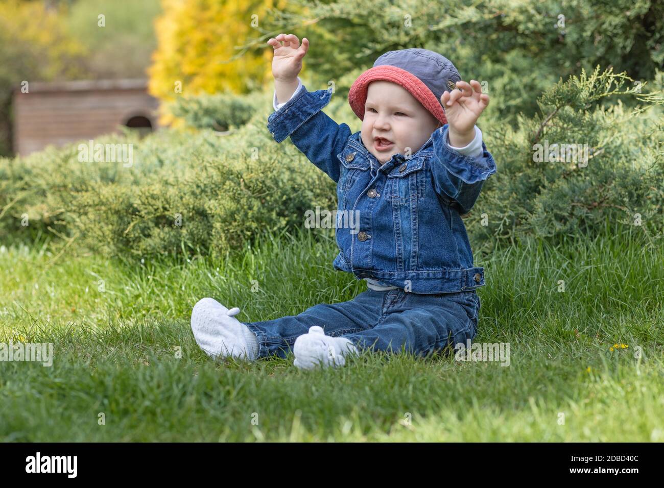 Cool little baby boy is sitting on the grass with arms raised Stock ...