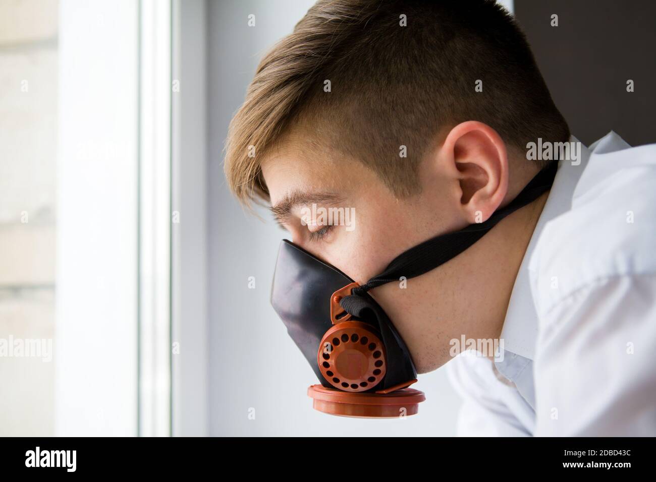 Sad Young Man in a Gas Mask by the Window in the Room Stock Photo - Alamy