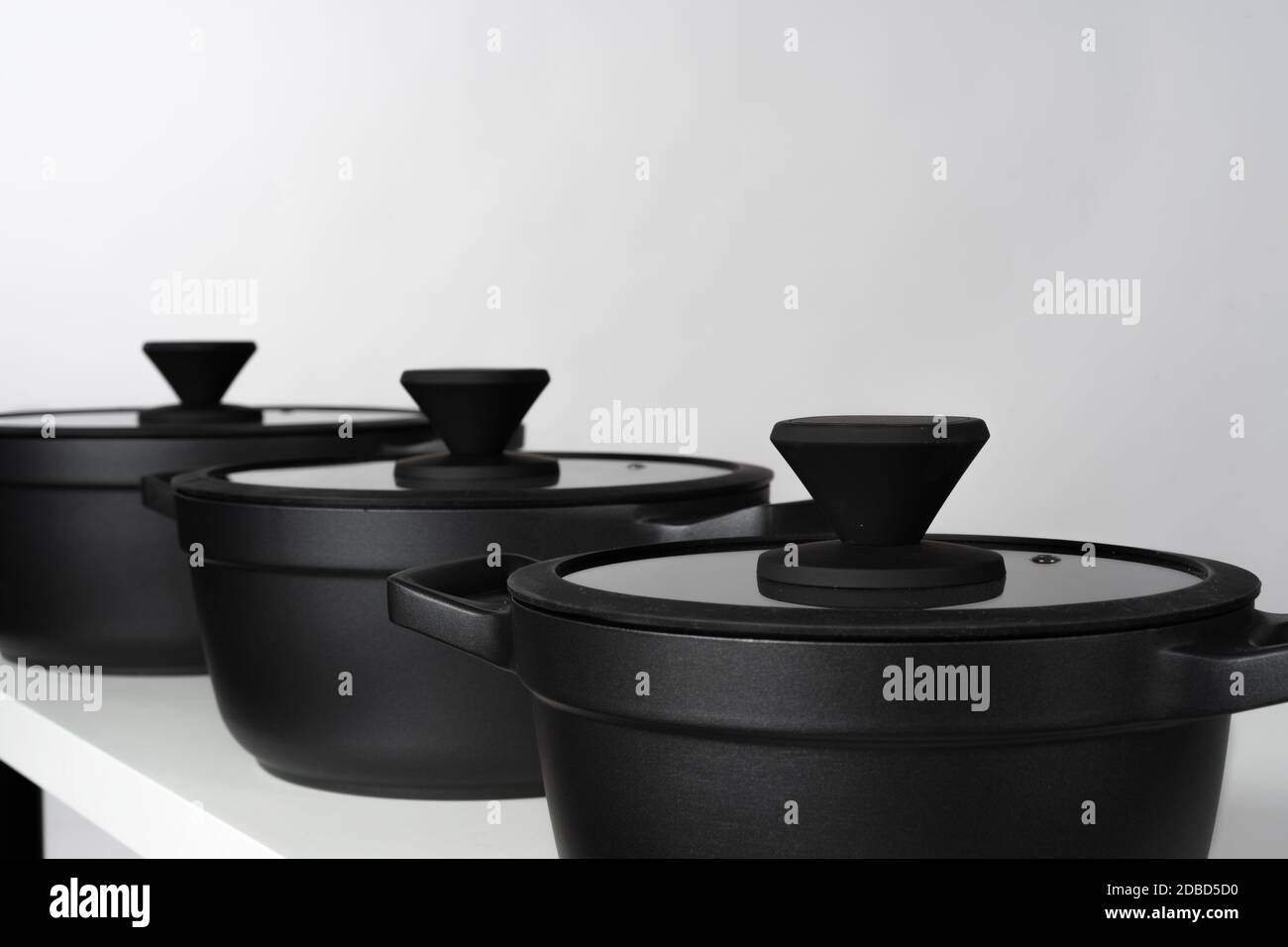 Black cooking pots on grey background front view Stock Photo - Alamy