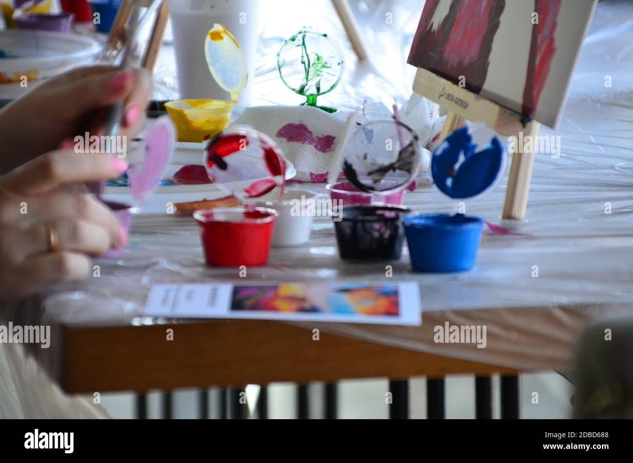 Pretty smiling young woman drawing a picture with paint. Front view on ...