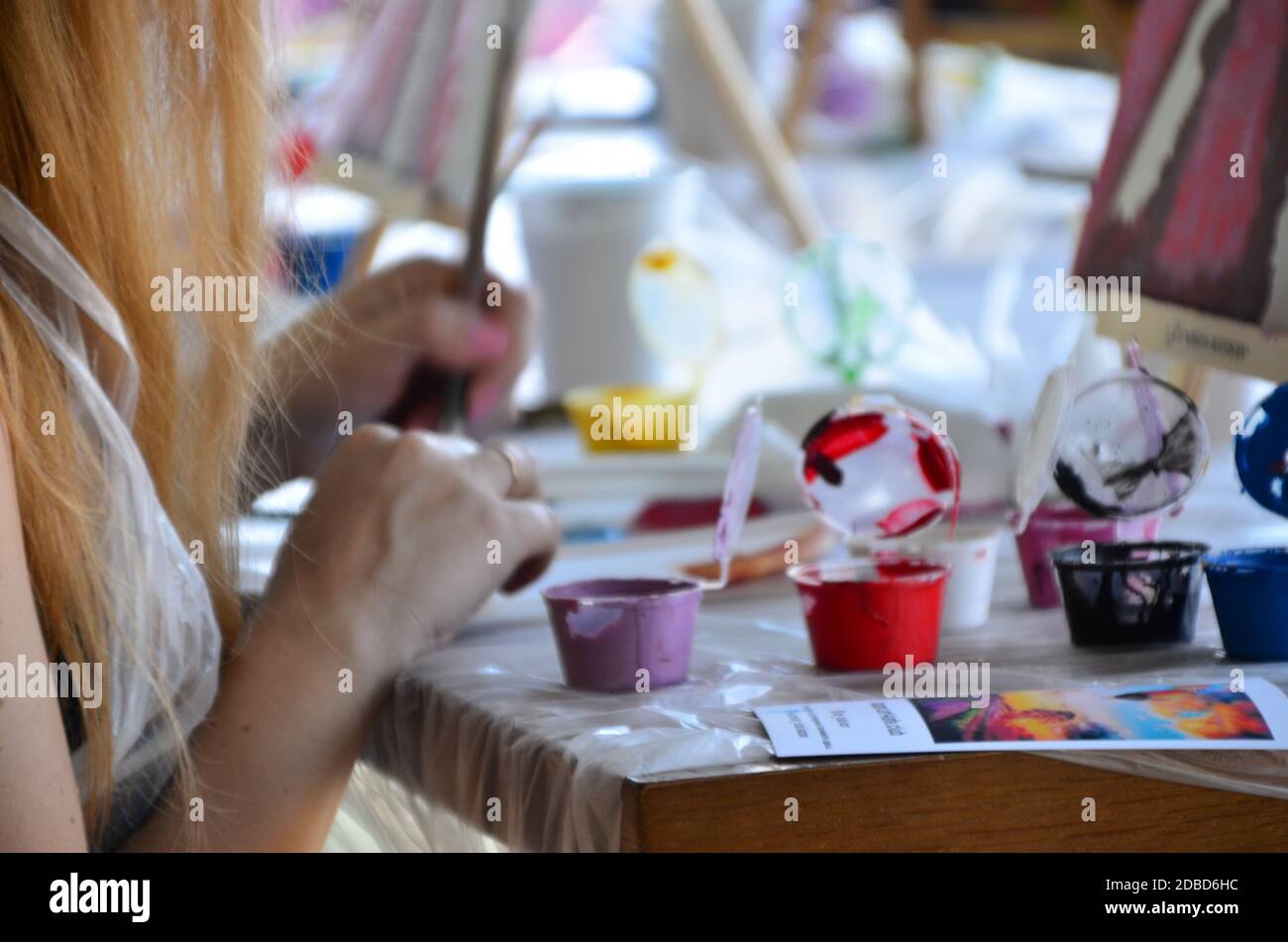 Pretty smiling young woman drawing a picture with paint. Front view on ...
