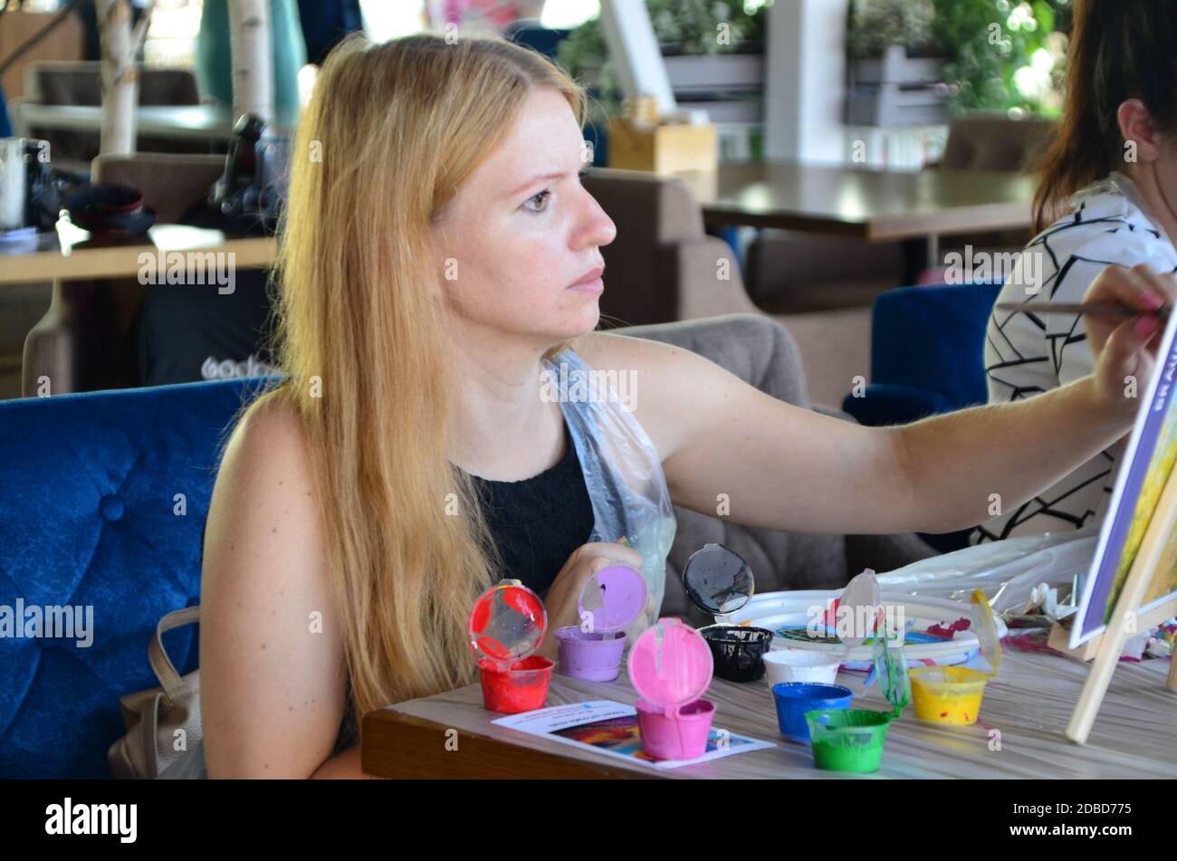 Pretty smiling young woman drawing a picture with paint. Front view on ...