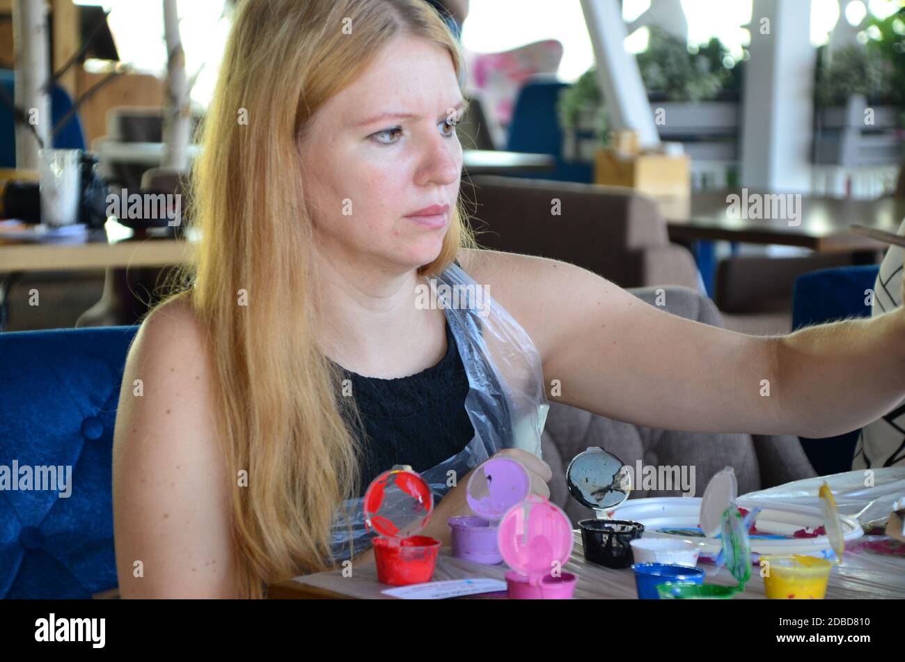 Pretty smiling young woman drawing a picture with paint. Front view on ...