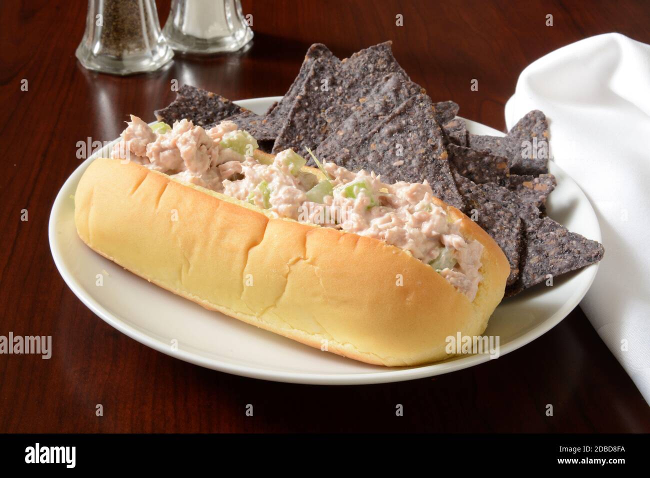 A tuna sandwich on a sub sandwich bun with blue corn tortilla chips ...