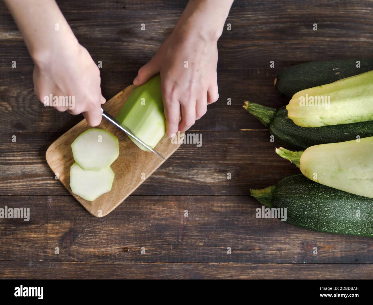 Zucchini harvest. Woman slices zucchini on wooden table. Farm organic ...