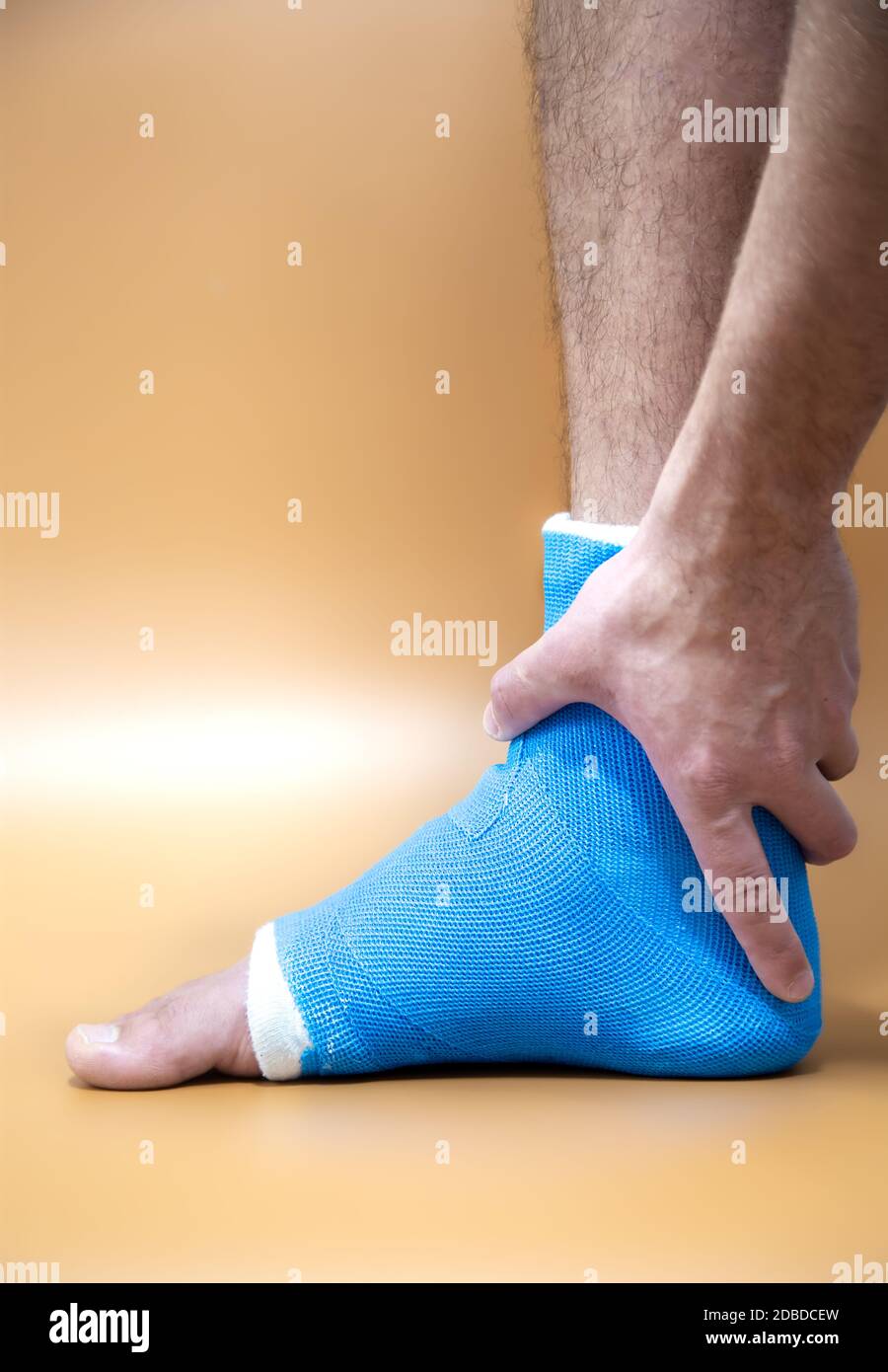 Blue splint ankle. Bandaged leg cast on male patient on colored blurred ...