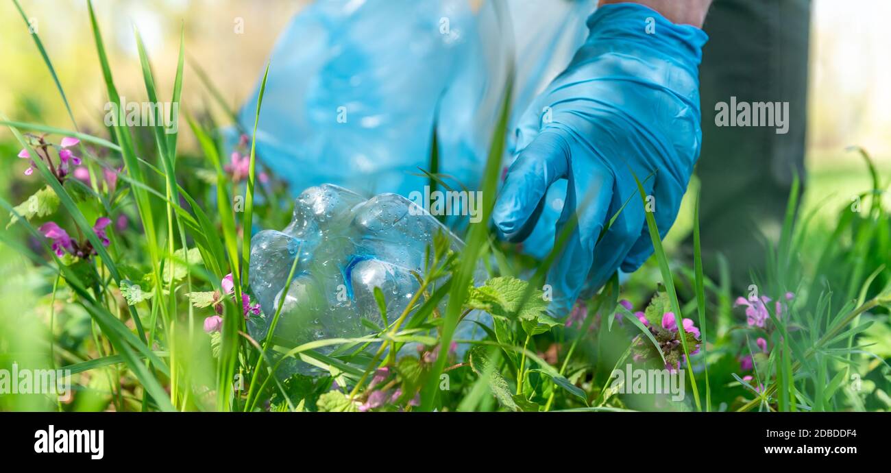 close-up on the hand of a man in rubber gloves collecting plastic waste ...