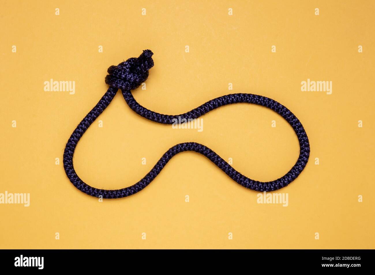 Close-up of black node with knot flat lay on a yellow background. Navy ...