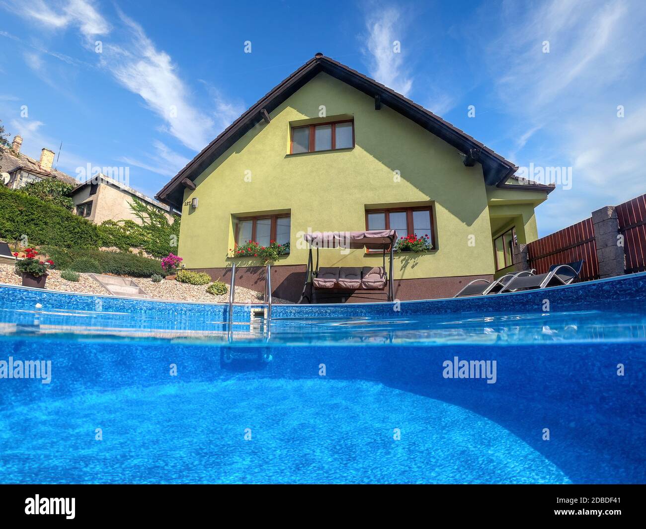 small home swimming pool with two black sun loungers and rocking bench ...