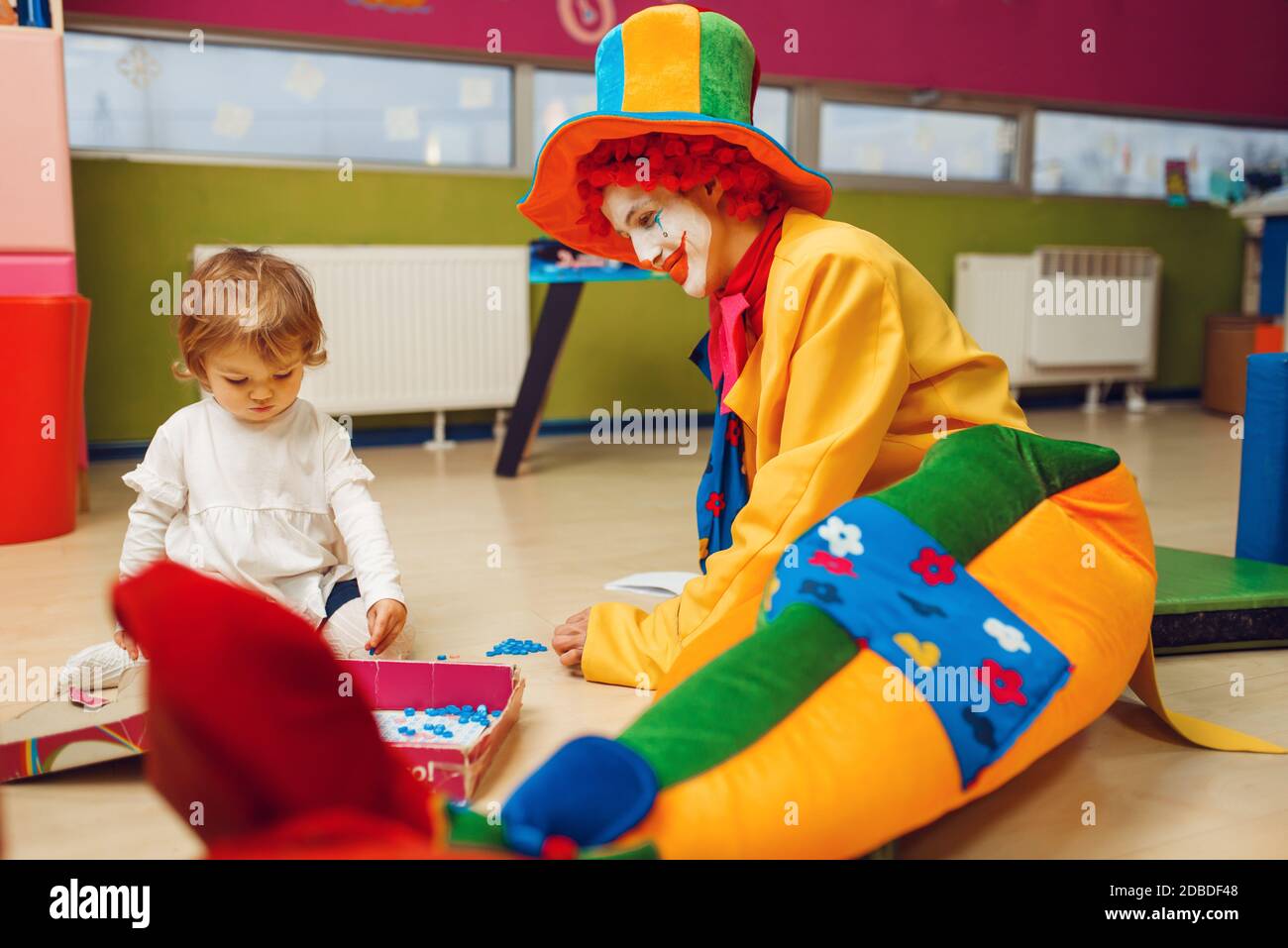 Funny clown play with joyful little girl together. Birthday celebrating ...