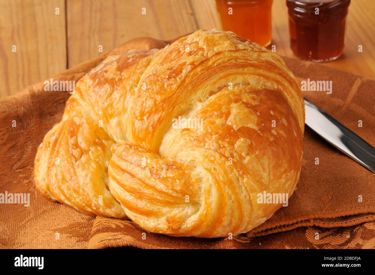 A large buttery croissant with small jars of jam Stock Photo - Alamy