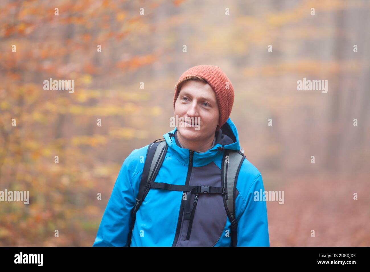 Young man hiking with backpack in a forest in fall - focus on the face ...