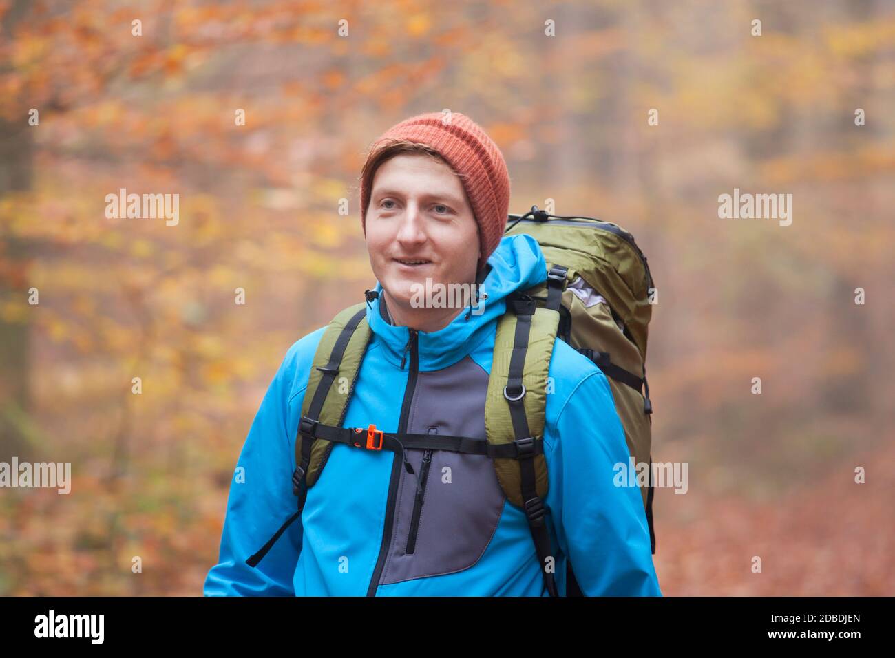 Young man hiking with backpack in a forest in fall - focus on the face ...