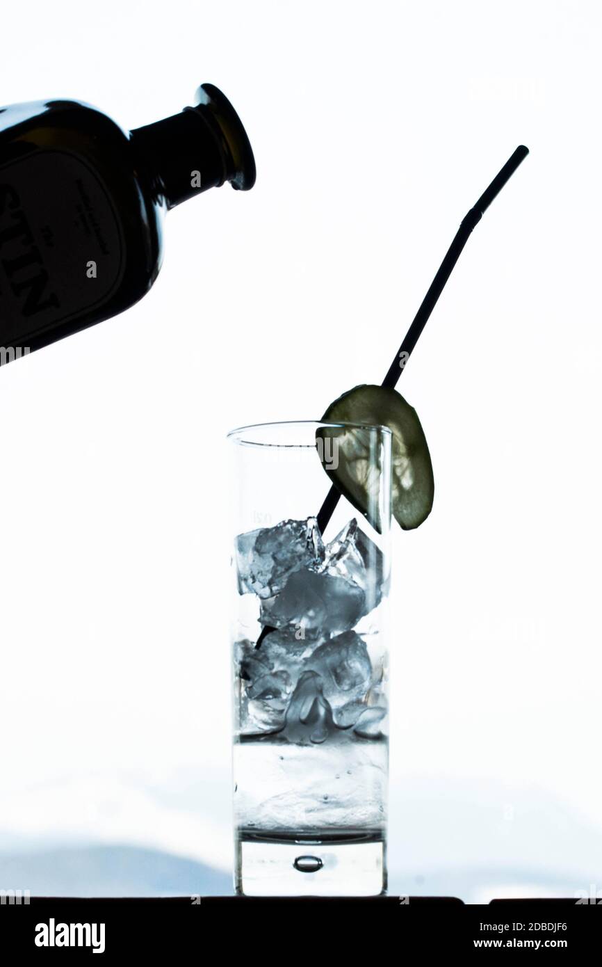 gin bottle, glass with ice cubes with a slice of cucumber, gin tonic ...