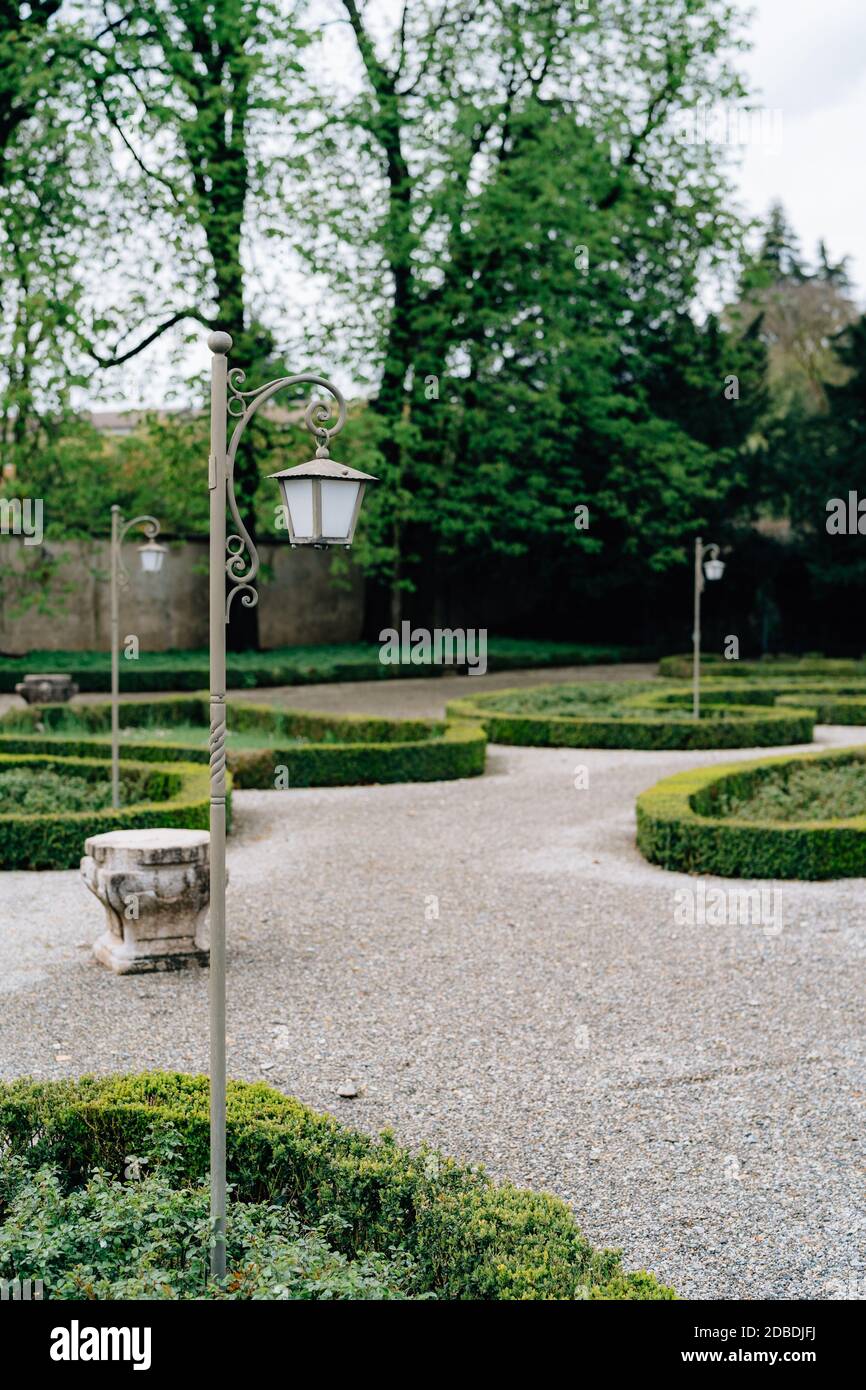 Gray street lamps in the grass on the park alley with manicured lawns ...