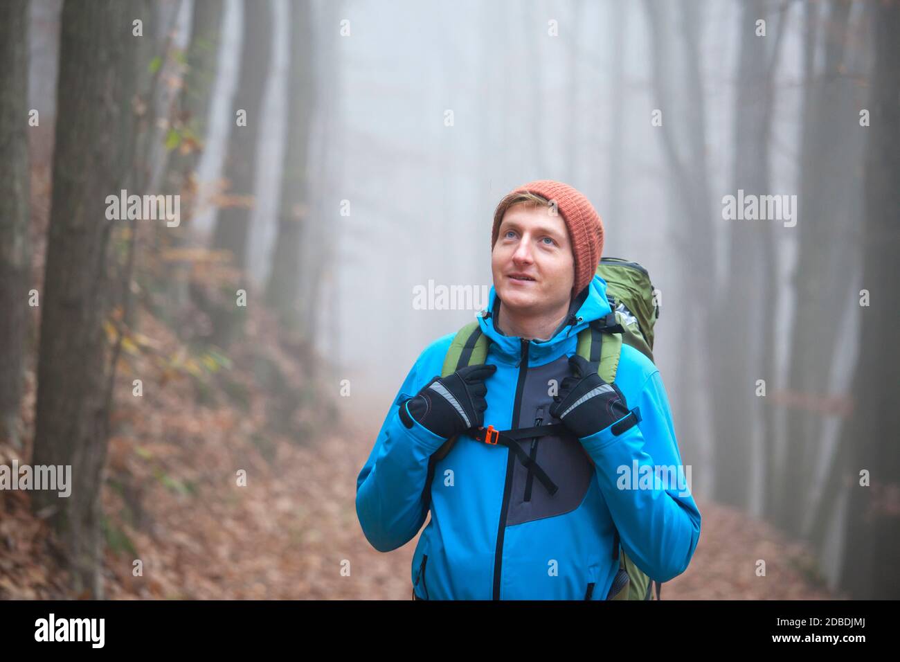 Young man hiking with backpack in a forest in winter - focus on the ...