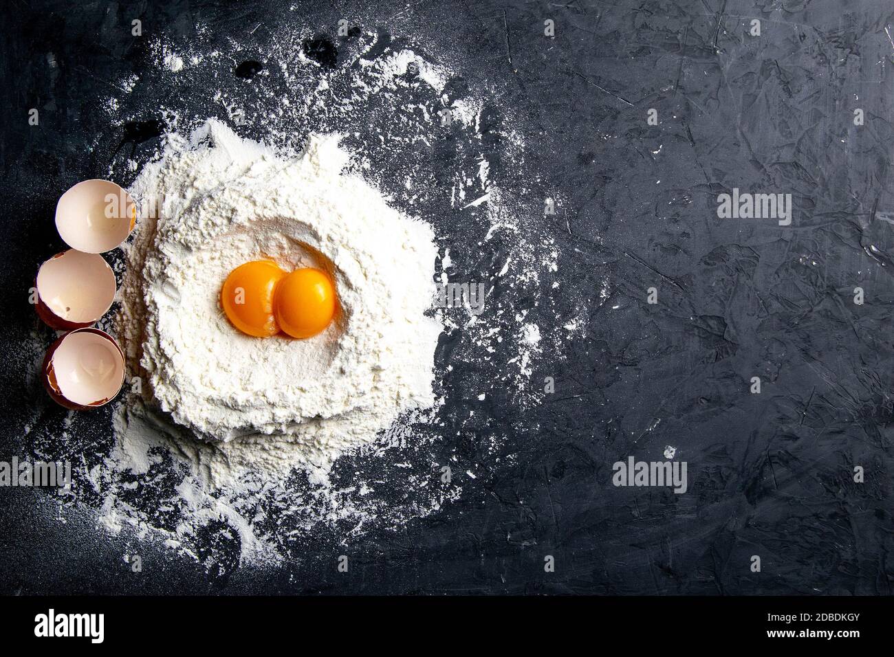 Pile of wheat flour and and egg yolk on a granite kitchen counter. Top ...