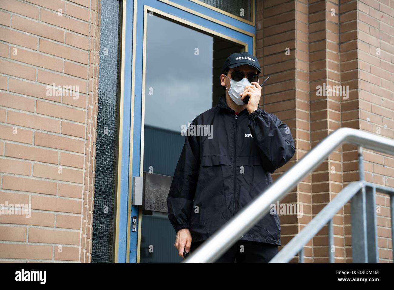 Security Guard In Face Mask Talking On Walkie Talkie Stock Photo - Alamy