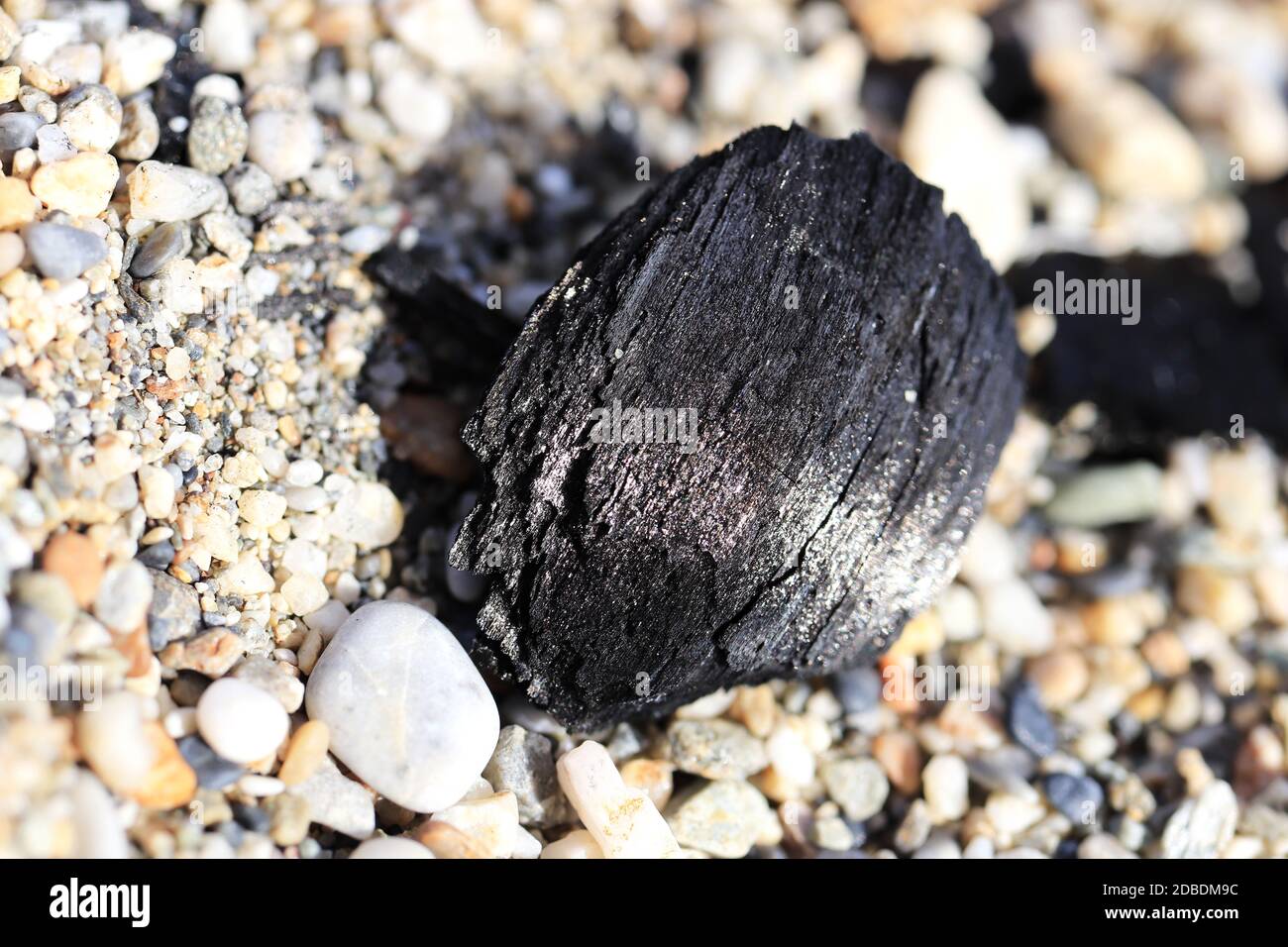 Coal on the beach stones Stock Photo - Alamy