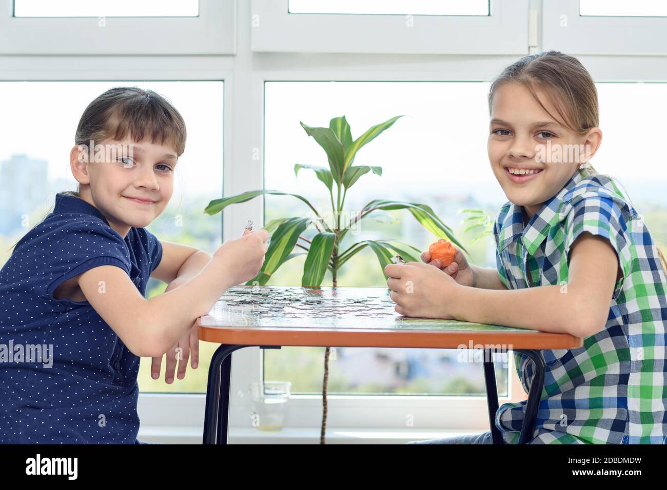 Children assemble a puzzle at home and happily look into the frame ...