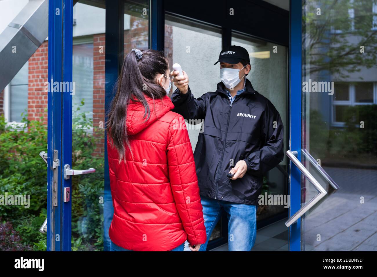 Security Guard Checking Temperature At Building Entrance Stock Photo ...