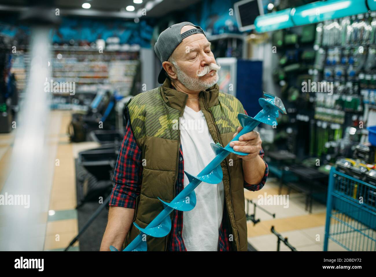 Fisherman holds a drill for winter fishing in shop. Male angler buying ...