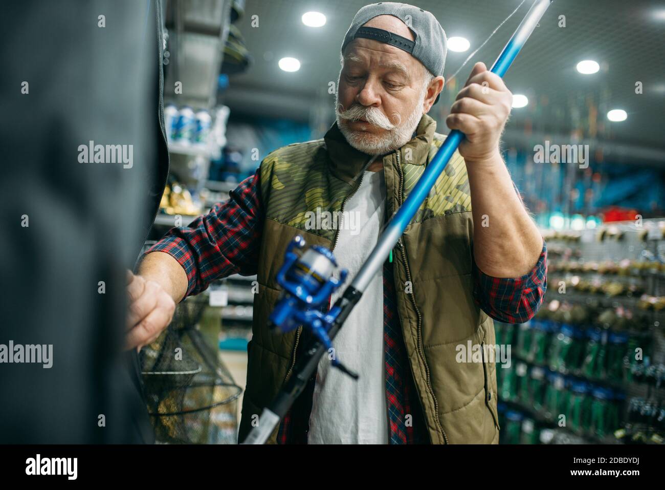 Male angler choosing rod in fishing shop. Equipment and tools for fish ...