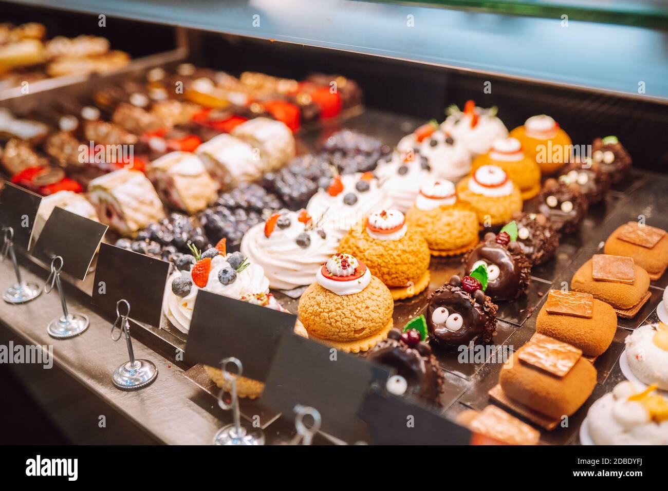 Different types of small cakes in candy store behind glass display ...