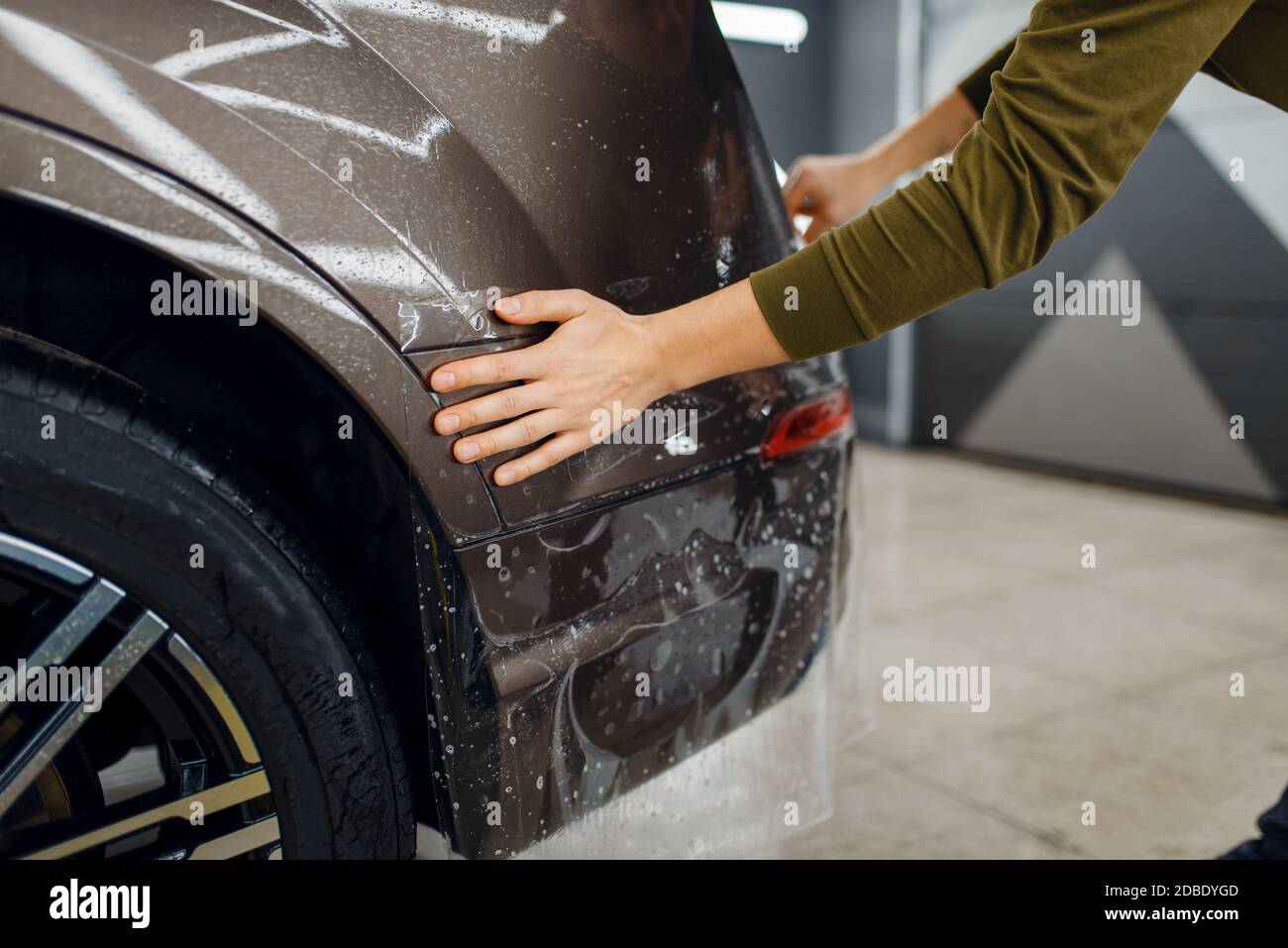 Worker applies car protection film on rear bumper. Installation of ...