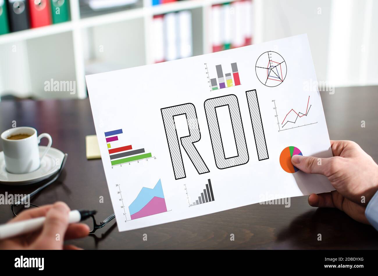 Hand holding a paper showing roi concept Stock Photo - Alamy