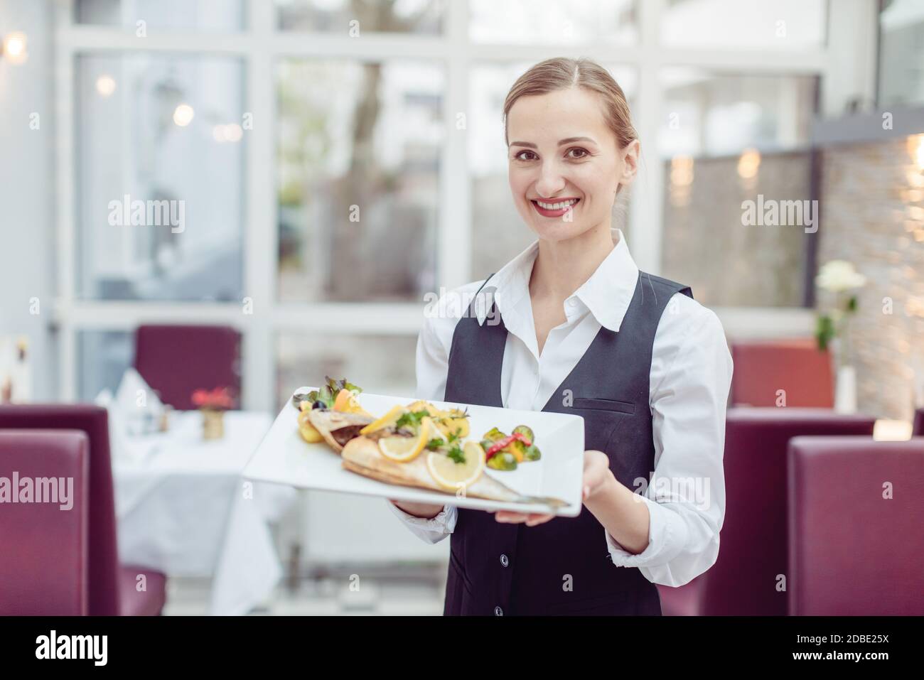 Waitress in a nice restaurant presenting a tasty dish to the camera ...