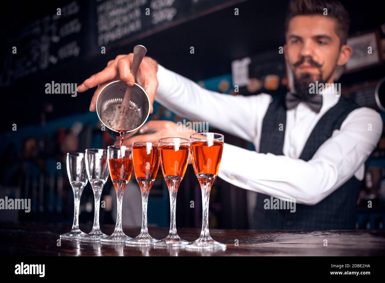 Charming bartending is pouring a drink while standing near the bar counter in bar Stock Photo ...