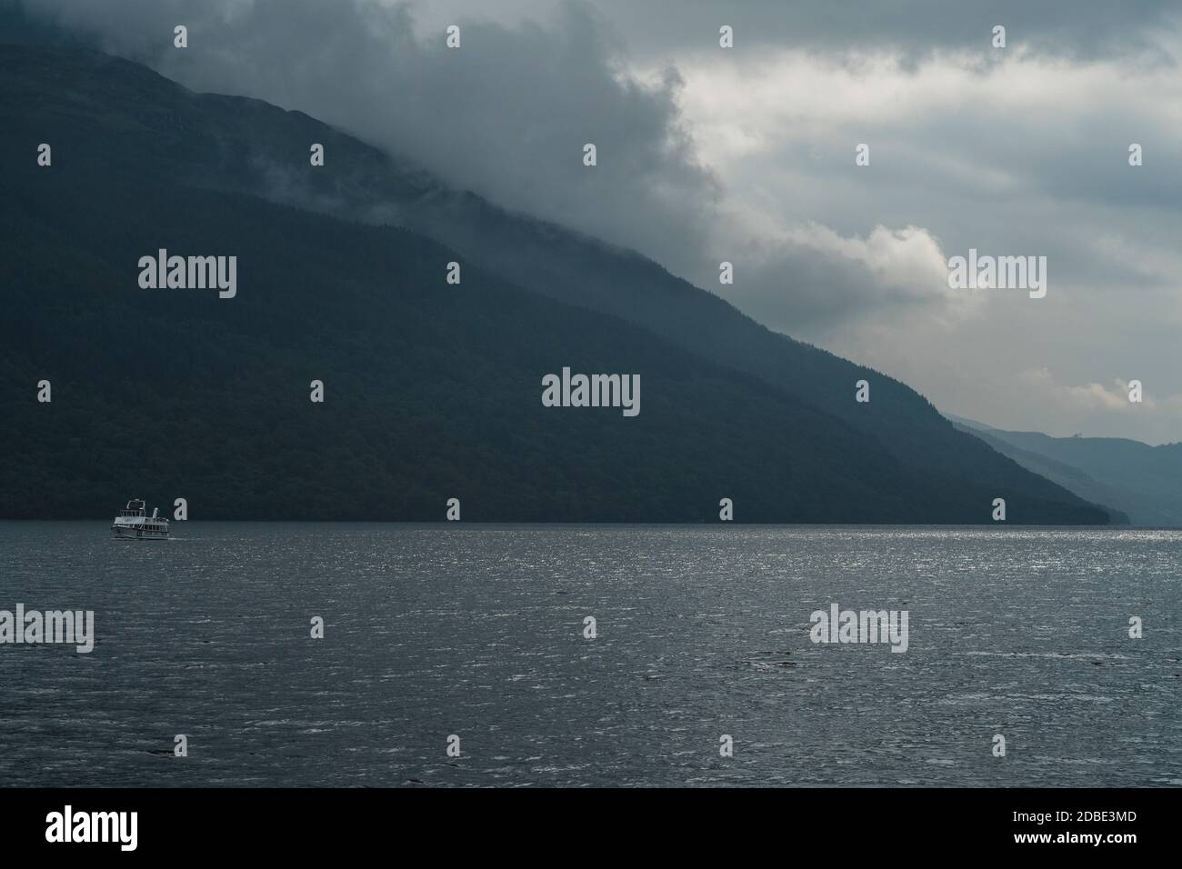 Lake with a boat in Scotland Highlands with calm sea and mountains ...