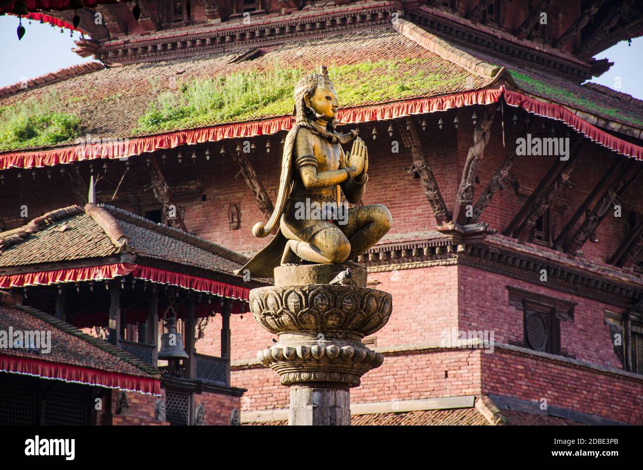 Statue of Malla King on top af o column, amongst Patan Durbar square ...