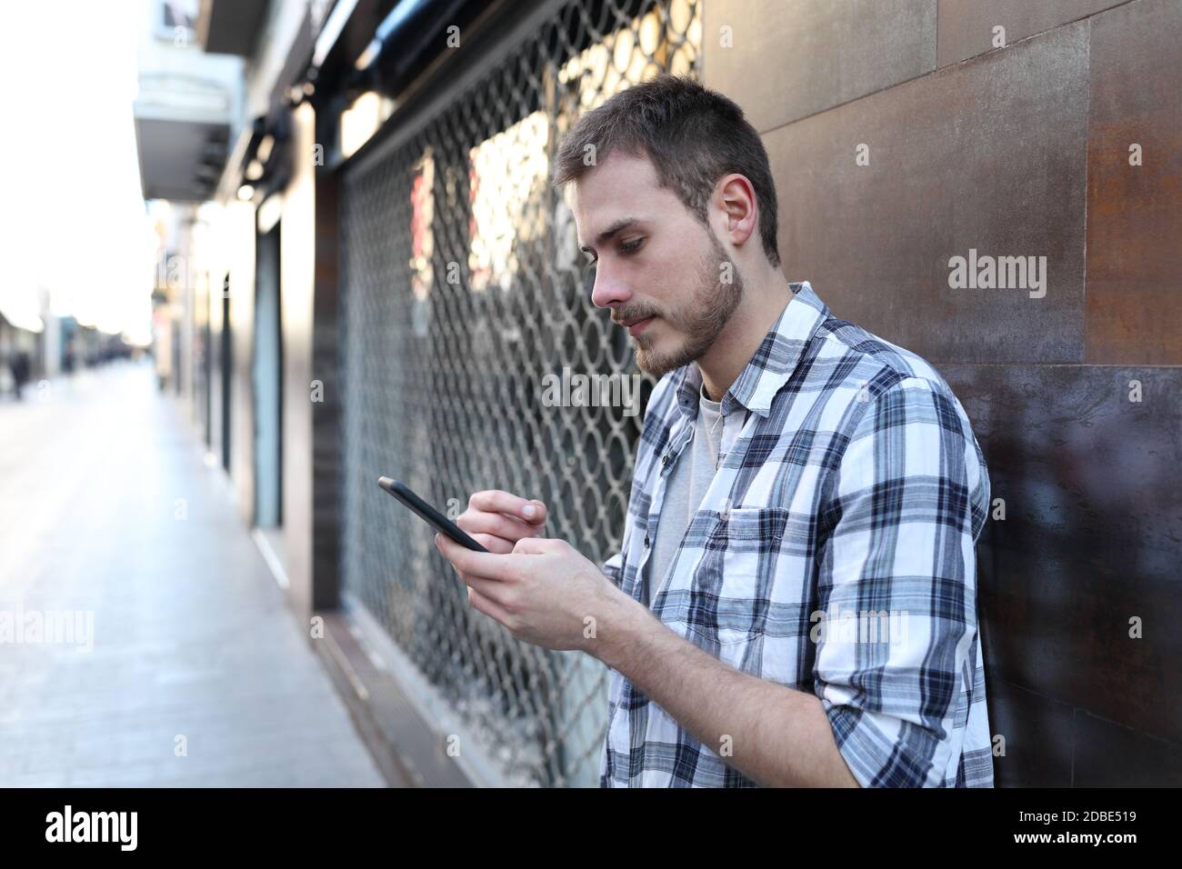 Side view portrait of a serious man using a smart phone in a street ...