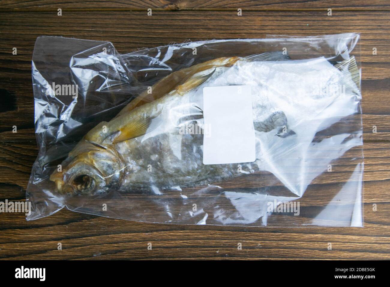Dried bream in a transparent package with a white label on a wooden ...