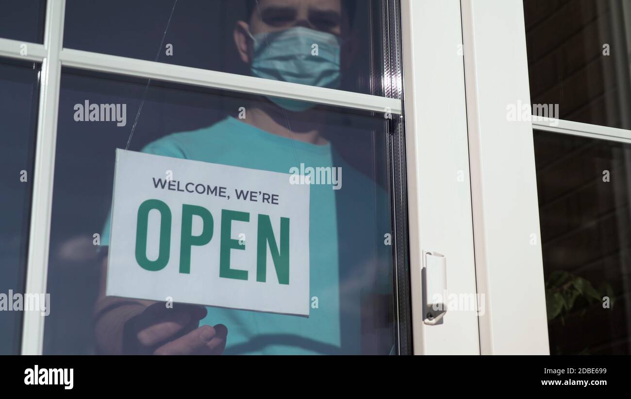 Close up of the male Caucasian hands turning a signboard on the glass ...