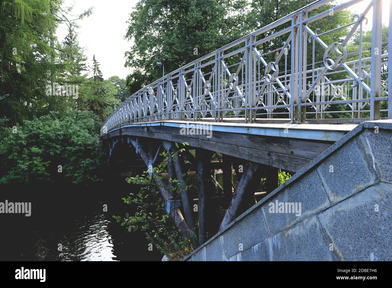 Concrete wood bridge with decorative ornaments on handrail. Park forest ...
