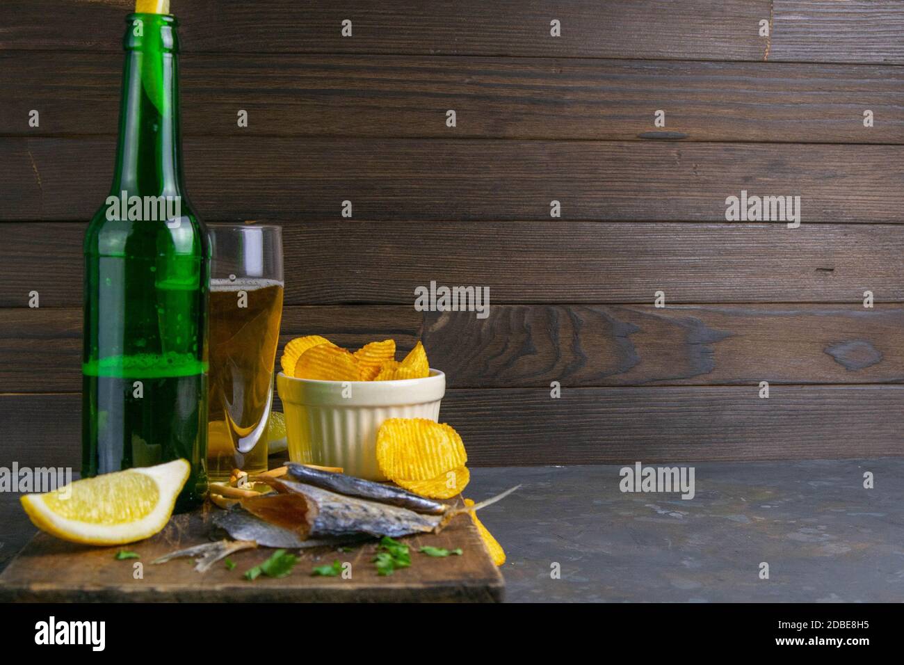 Dried bream in form butterfly with beer, lemon and potato chips on dark ...