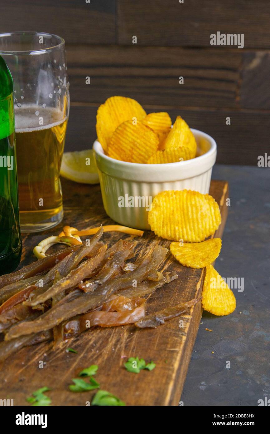 Dried carp fish sticks with beer, lemon and potato chips on dark wooden ...